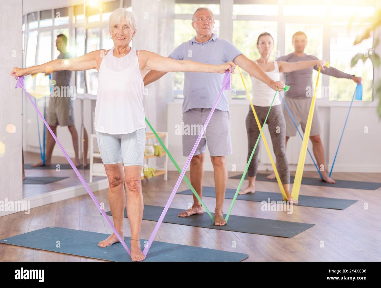 Elderly woman during Pilates strength training standing performs ...