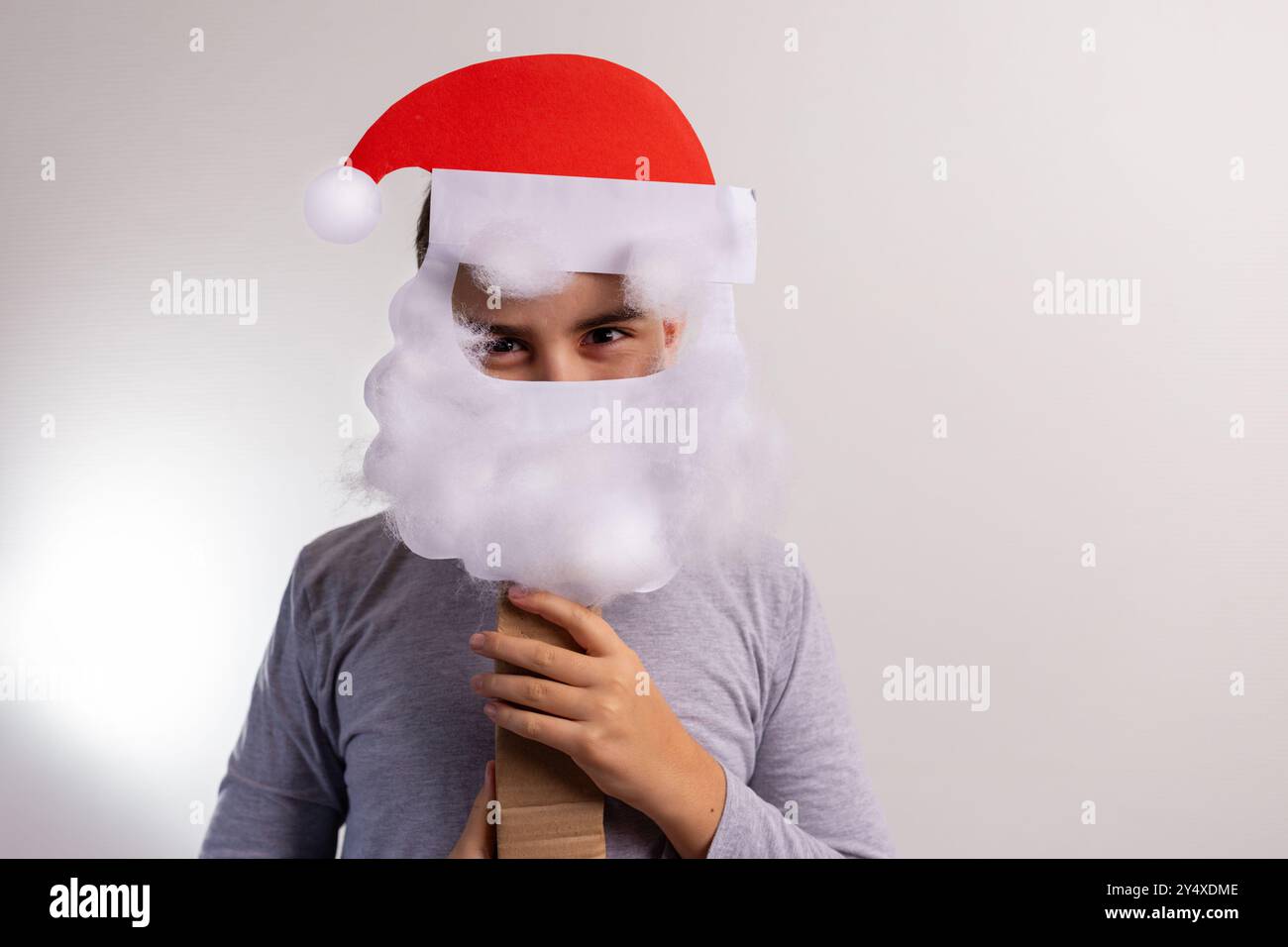 a boy wearing a paper craft Santa hat and beard, disguise New Year mask ...