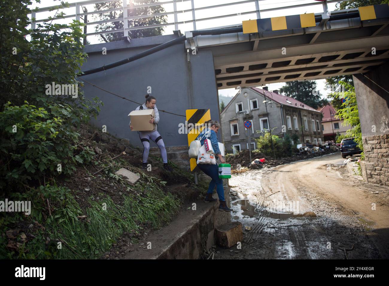 Two women carrying bags walk down the side of a train bridge since the ...