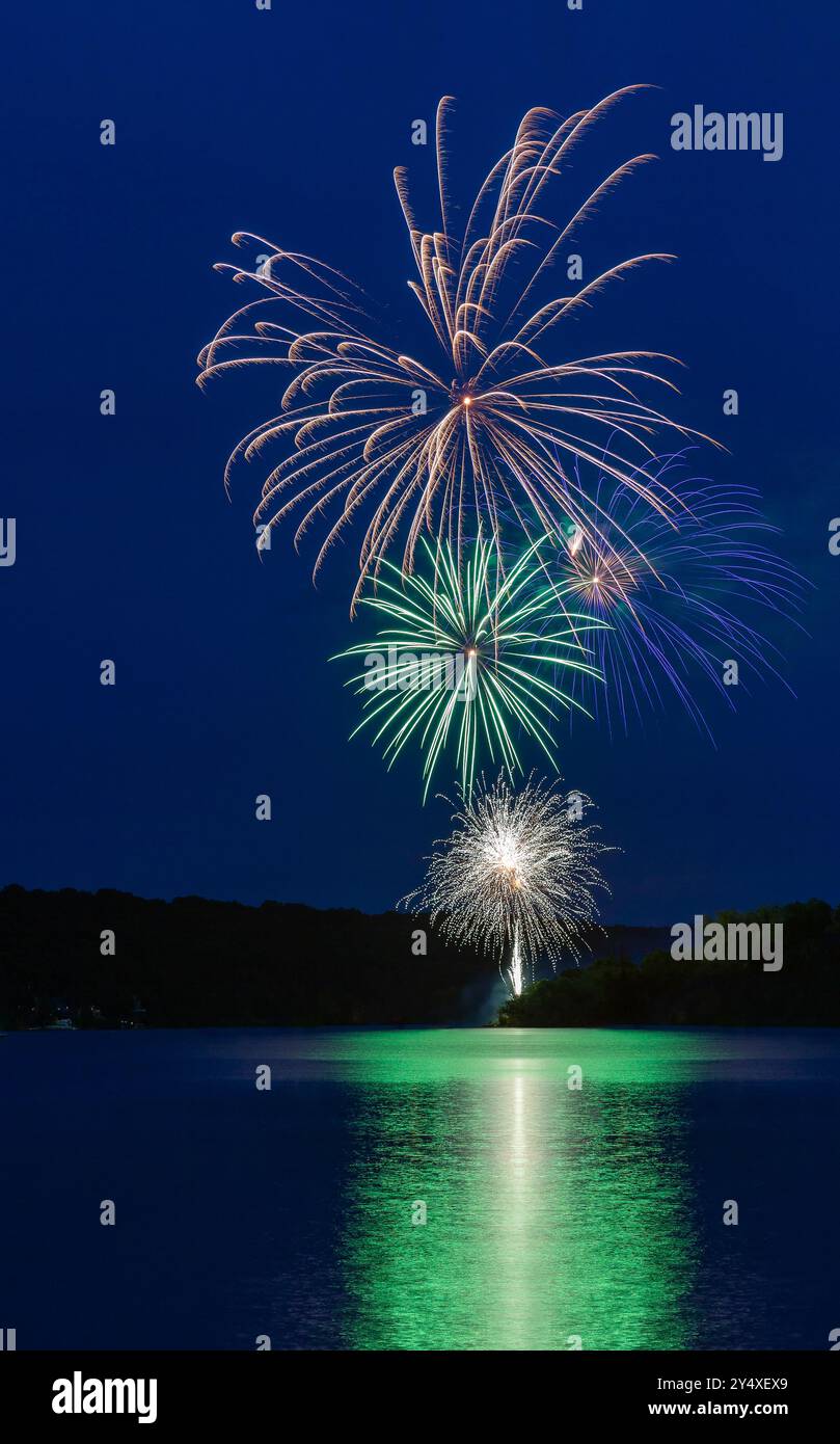 Colorful fireworks exploding over water with green and white ...