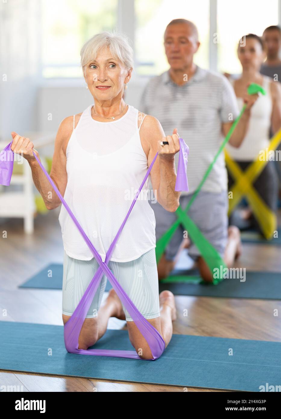 Elderly woman performs exercises with elastic band during Pilates ...