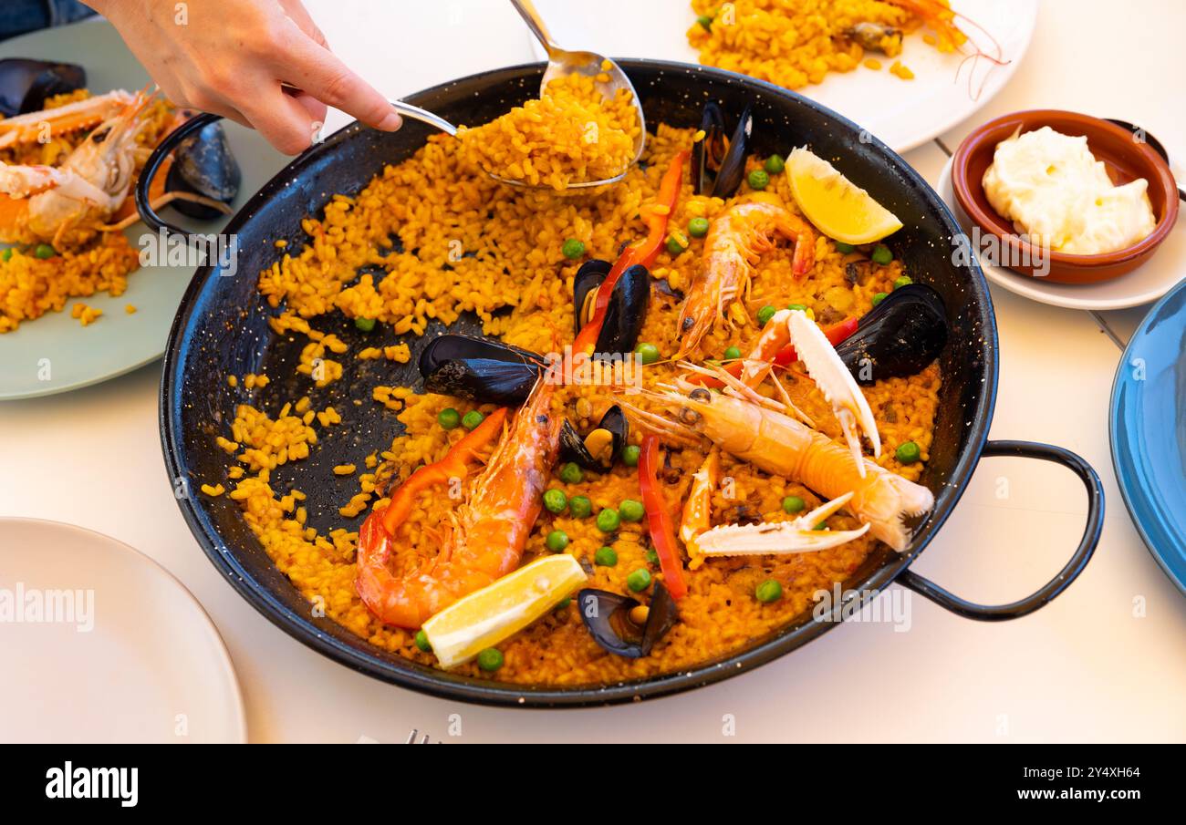 Womens hands lay out sea paella in plates for family dinner Stock Photo ...