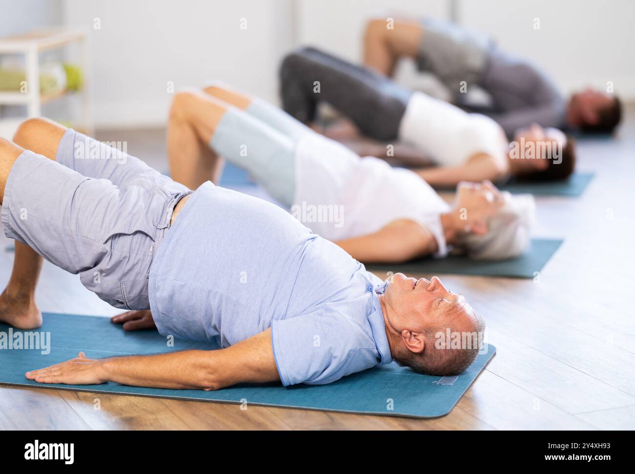 Elderly man performs glute bridge during Pilates training Stock Photo ...