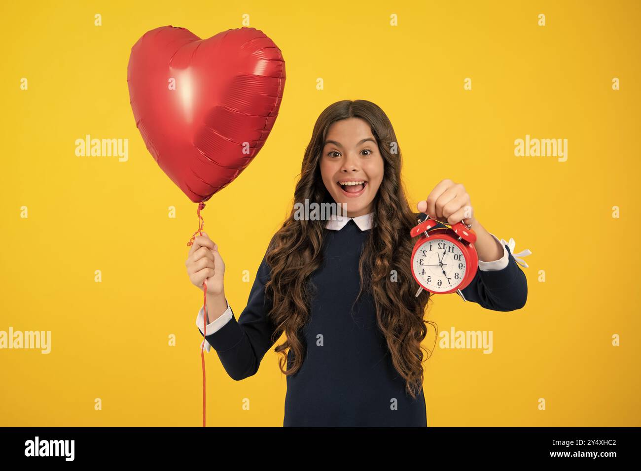 Teen student girl hold clock isolated on yellow background. Time to ...