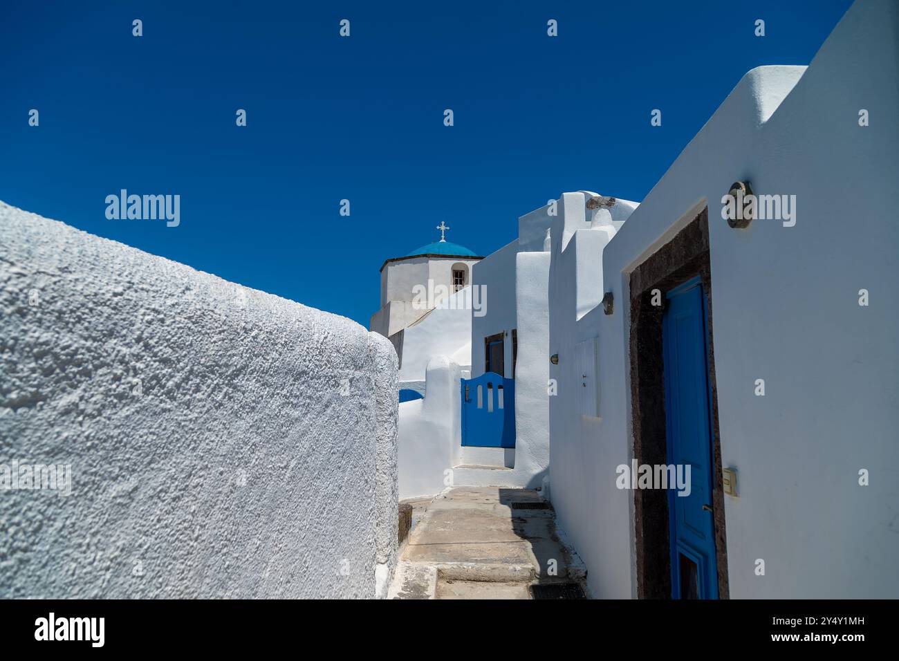Whitewashed walls, steps, blue domed Orthodox church, white cross. A ...