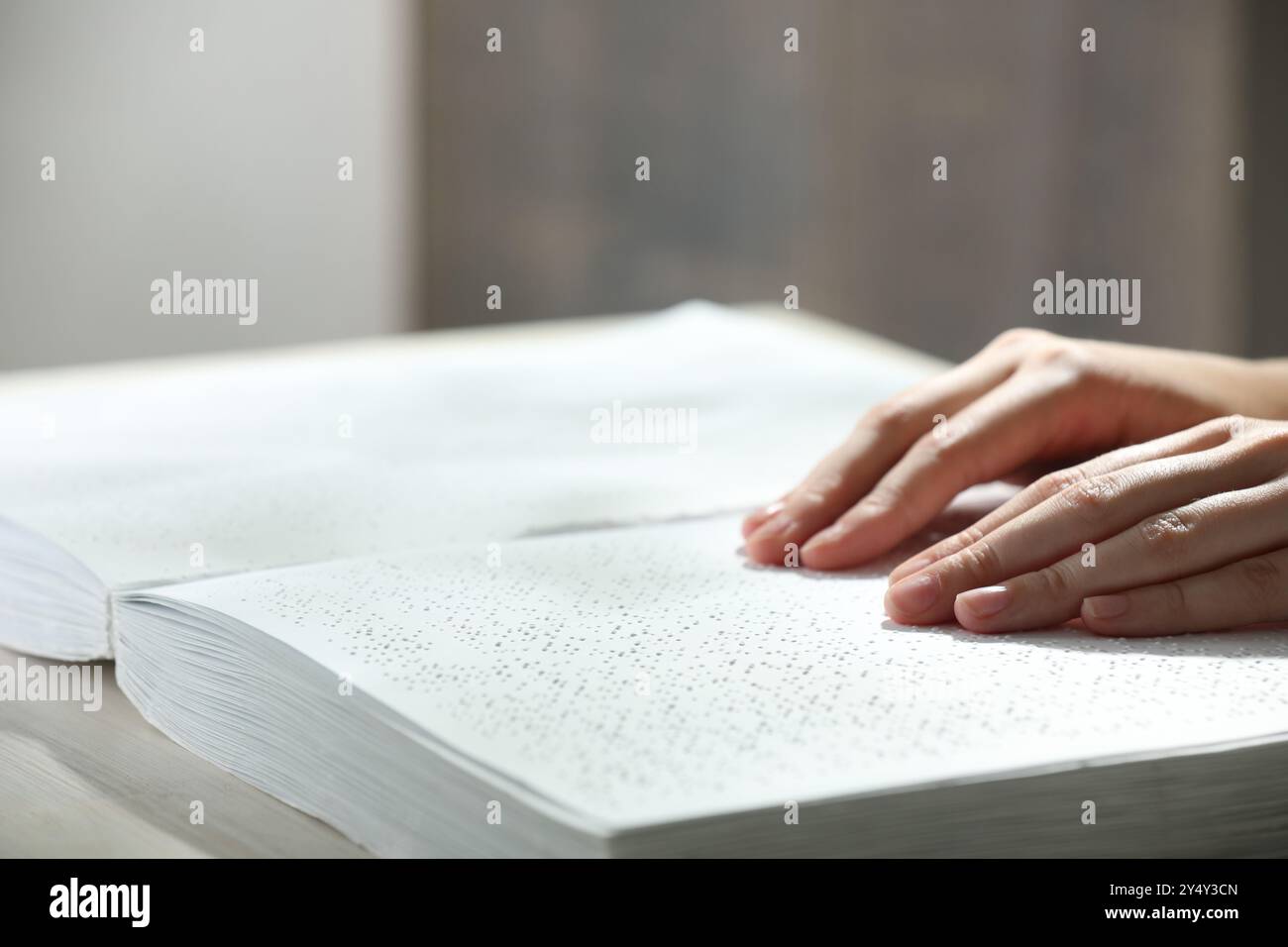 Blind woman reading book written in Braille at wooden table, closeup ...
