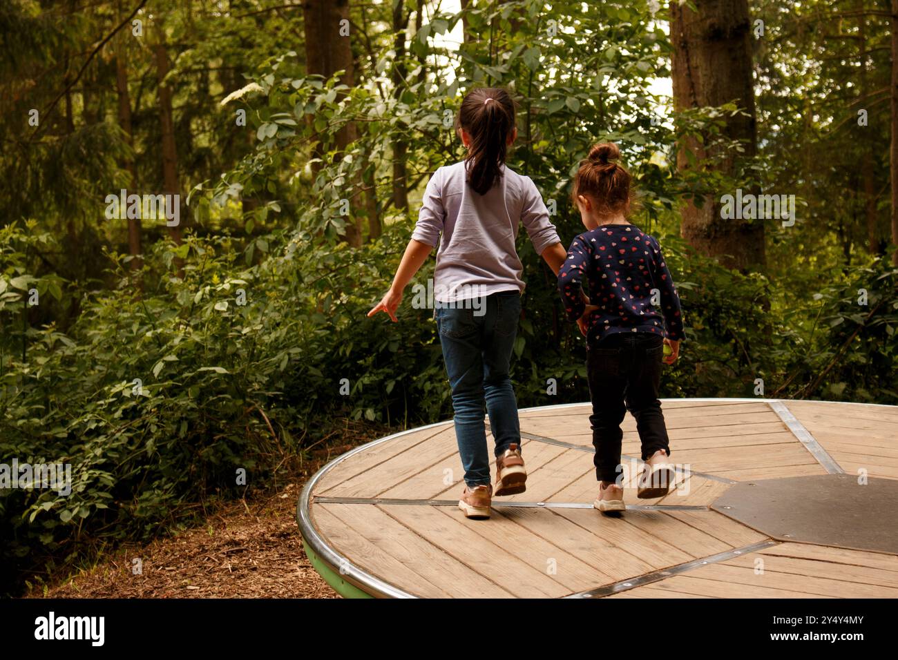 Two girls on a carousel in a summer park. Child friendship concept ...