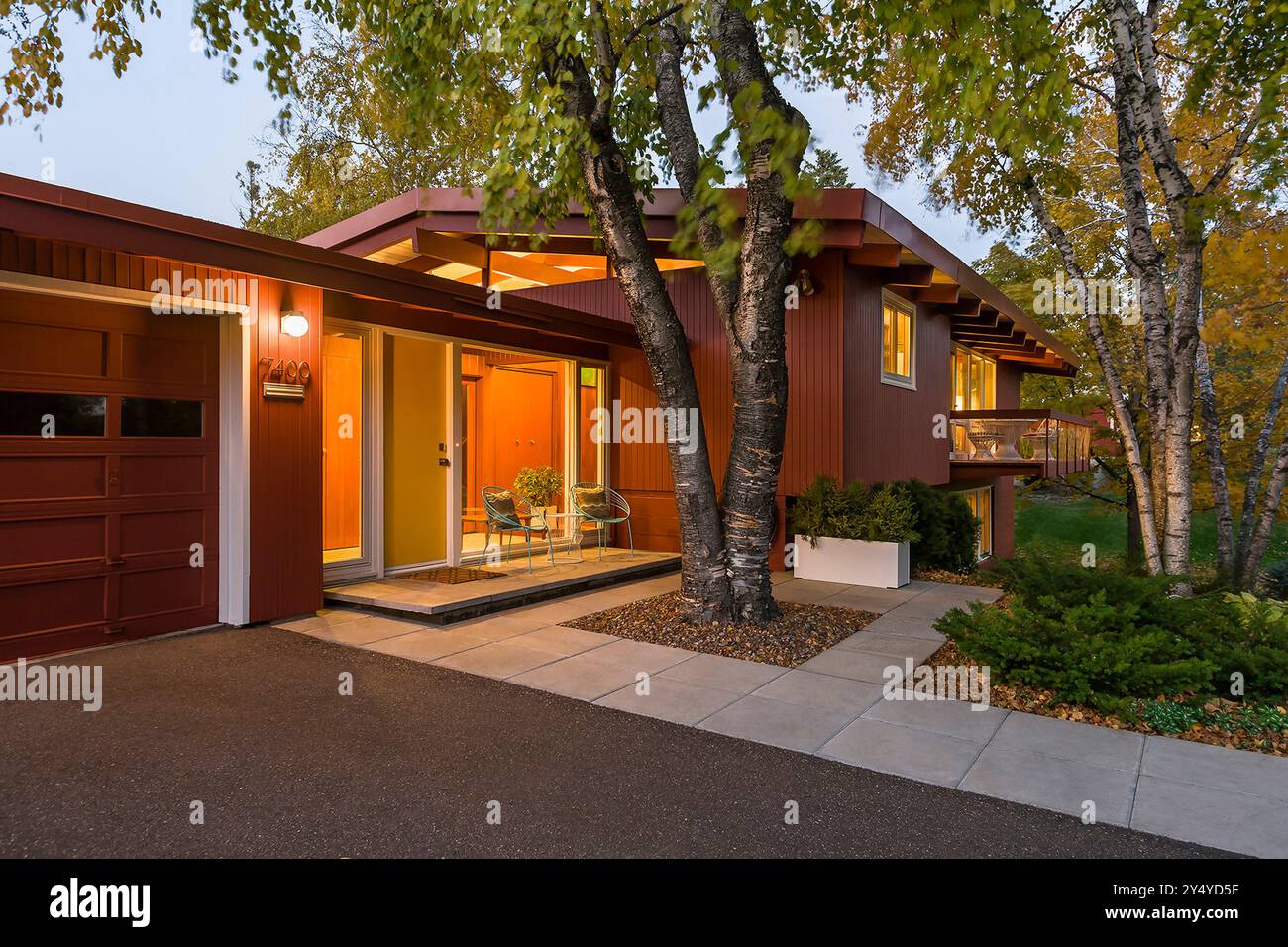 Front exterior of red mid-century split level rambler at dusk - angle ...