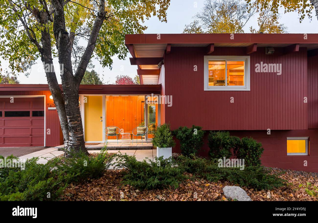 Front exterior of red mid-century split level rambler at late dusk ...