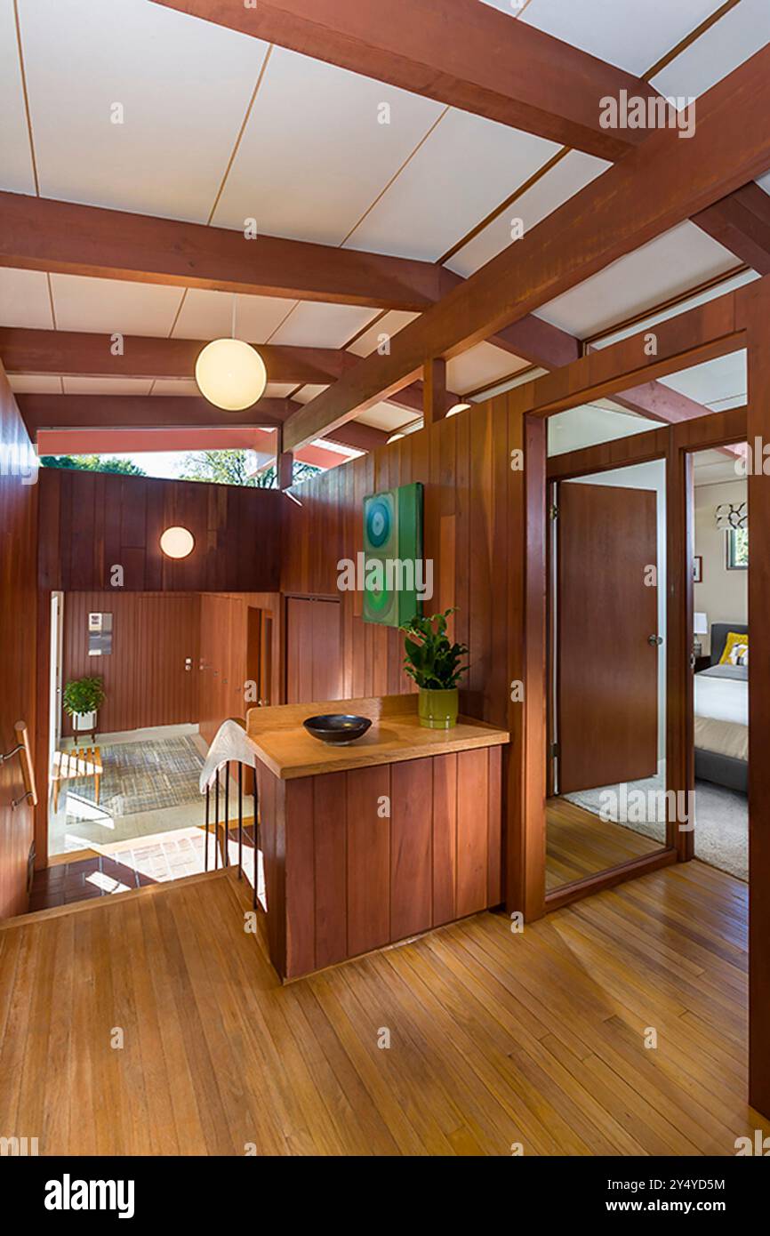 Hallway of remodeled mid-century house with warm redwood paneling and ...