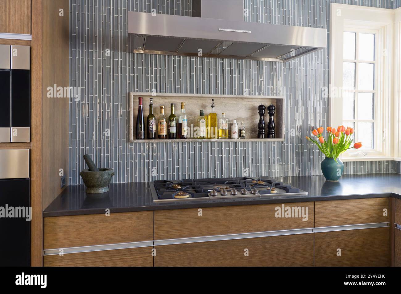 Corner of modern kitchen showing cooktop, window and unique backsplash ...