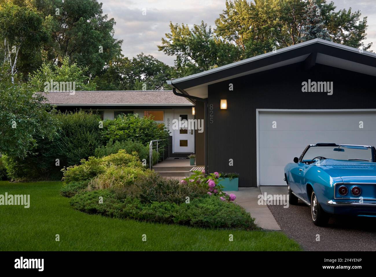 Exterior of split level rambler with blue Corvair parked in driveway ...