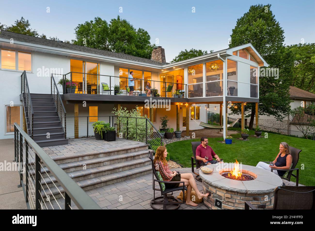 People enjoying backyard of house with firepit and upper level deck and ...