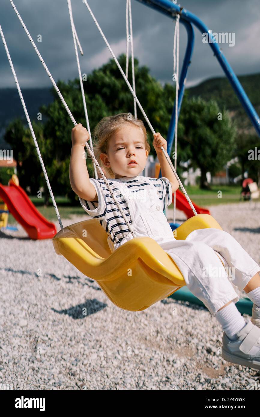 Little girl swings on a rope swing at the playground Stock Photo - Alamy