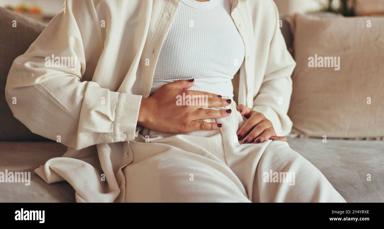 Woman, hands and stomach pain of menstruation on sofa with period ...