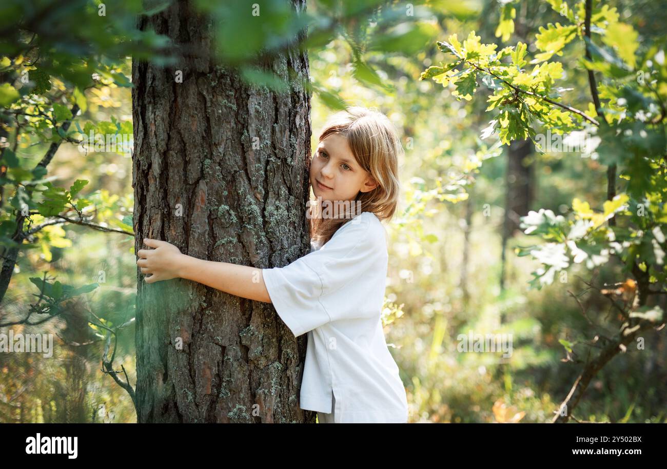 A teenage girl hugs a tree in the forest. Hugging and touching trees to ...
