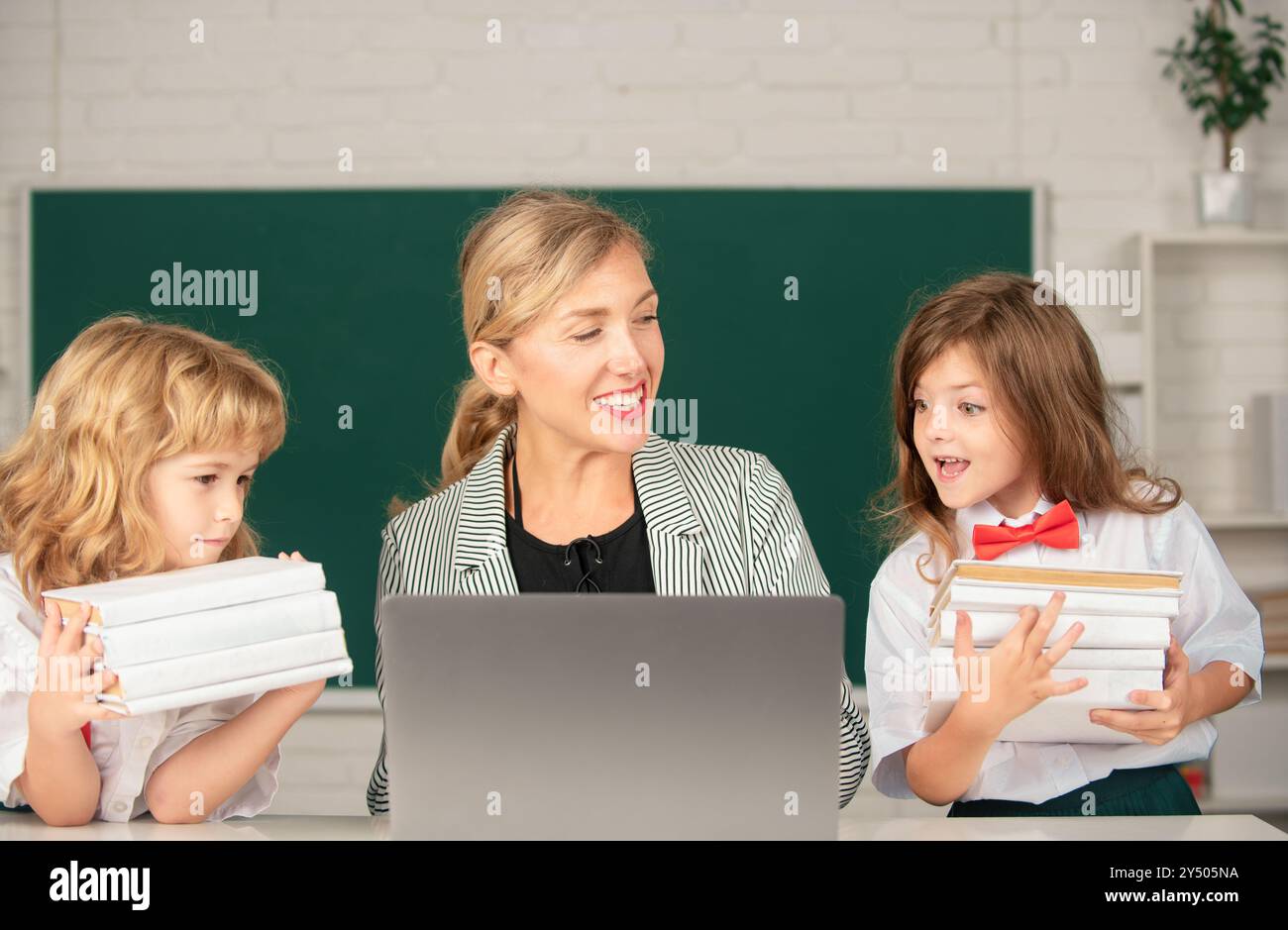 School teacher with a schoolkids learning at laptop computer, studying ...