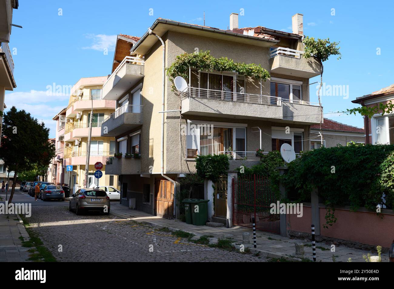 A lively city street features residential buildings adorned with ...