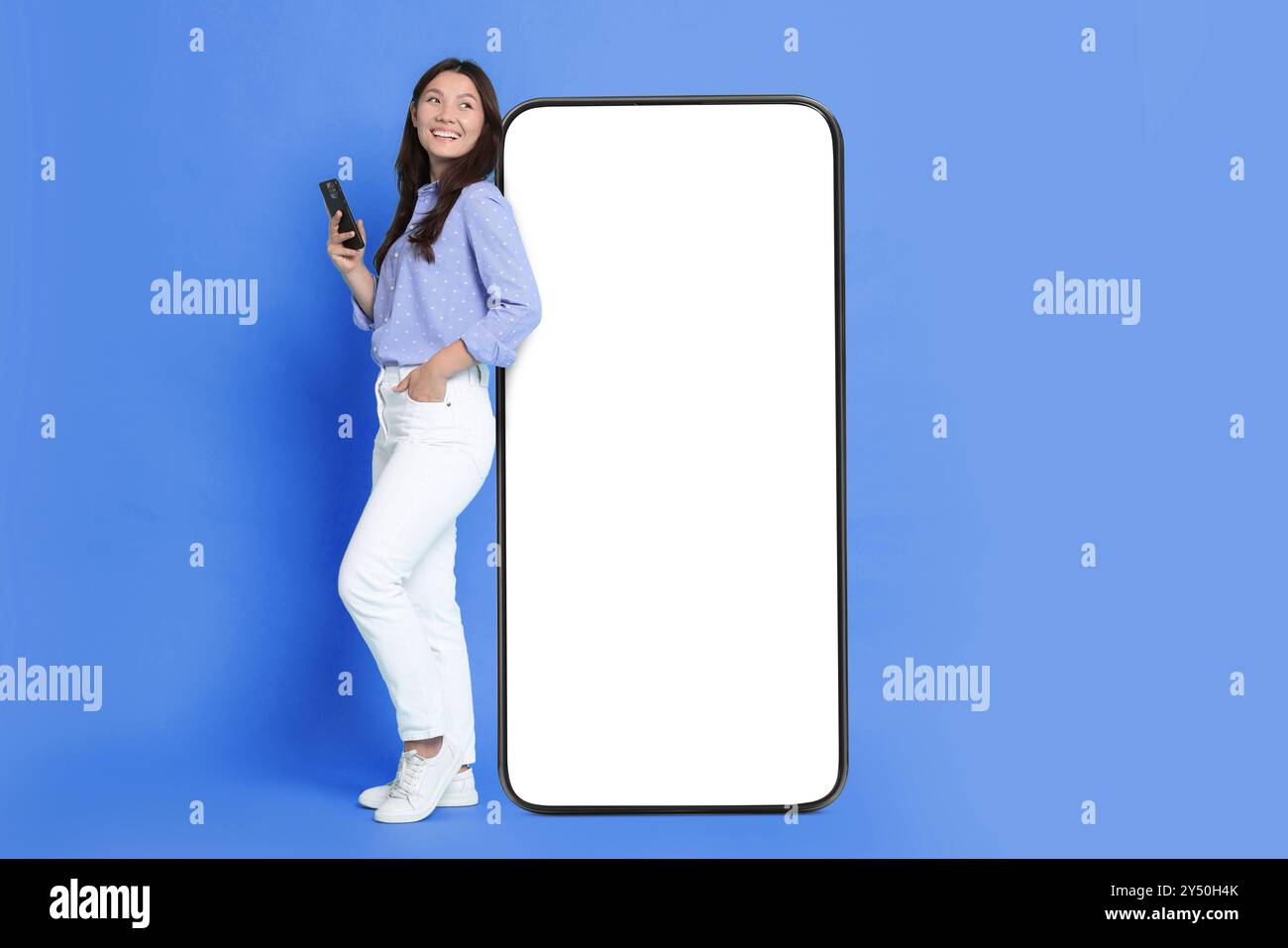 Happy smiling woman with smartphone standing near big mobile phone with ...