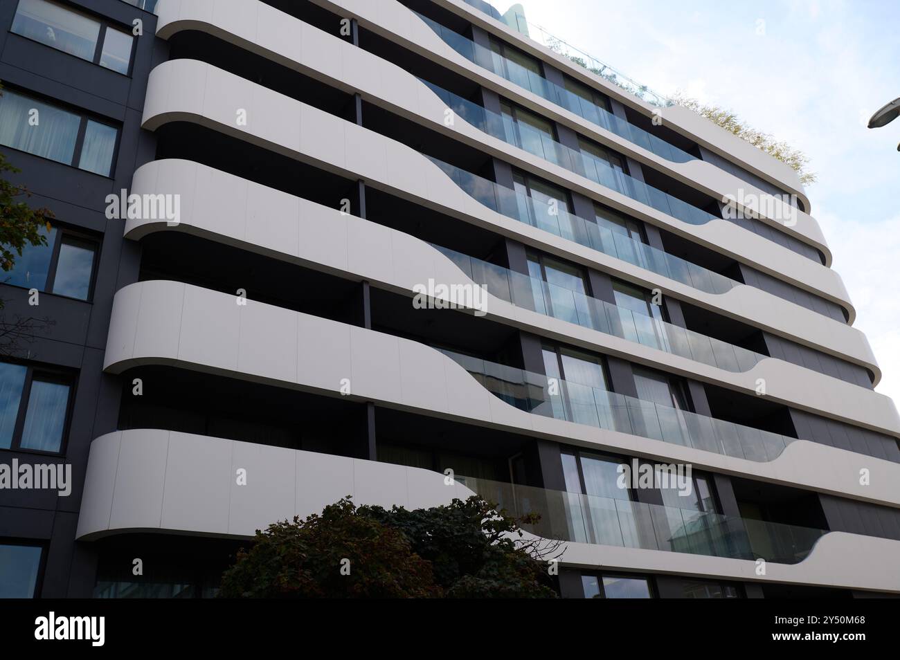 Modern architectural design of a sleek residential building featuring curved balconies in an ...