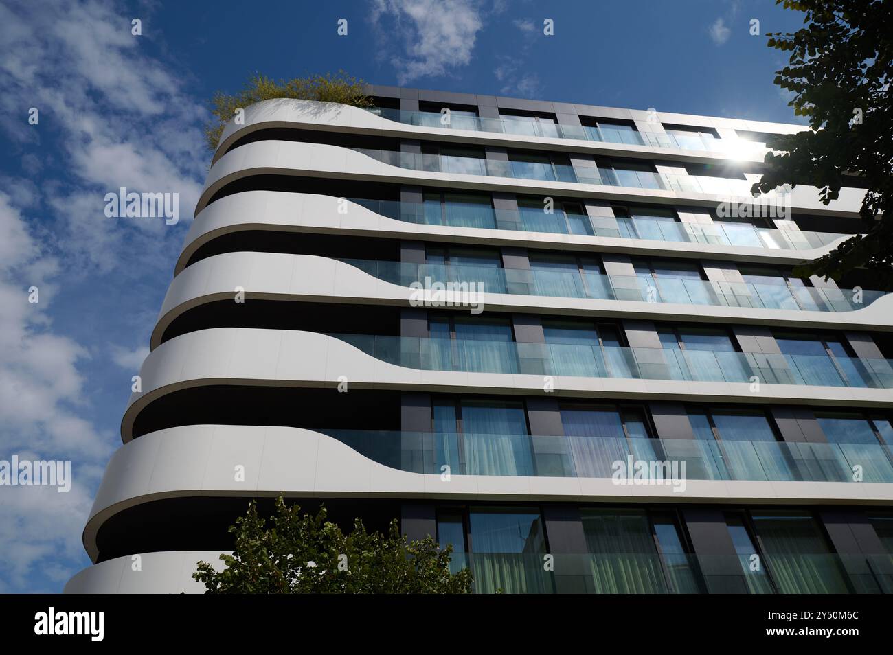 Modern architectural design featuring a sleek, curved facade in an urban setting under a clear ...