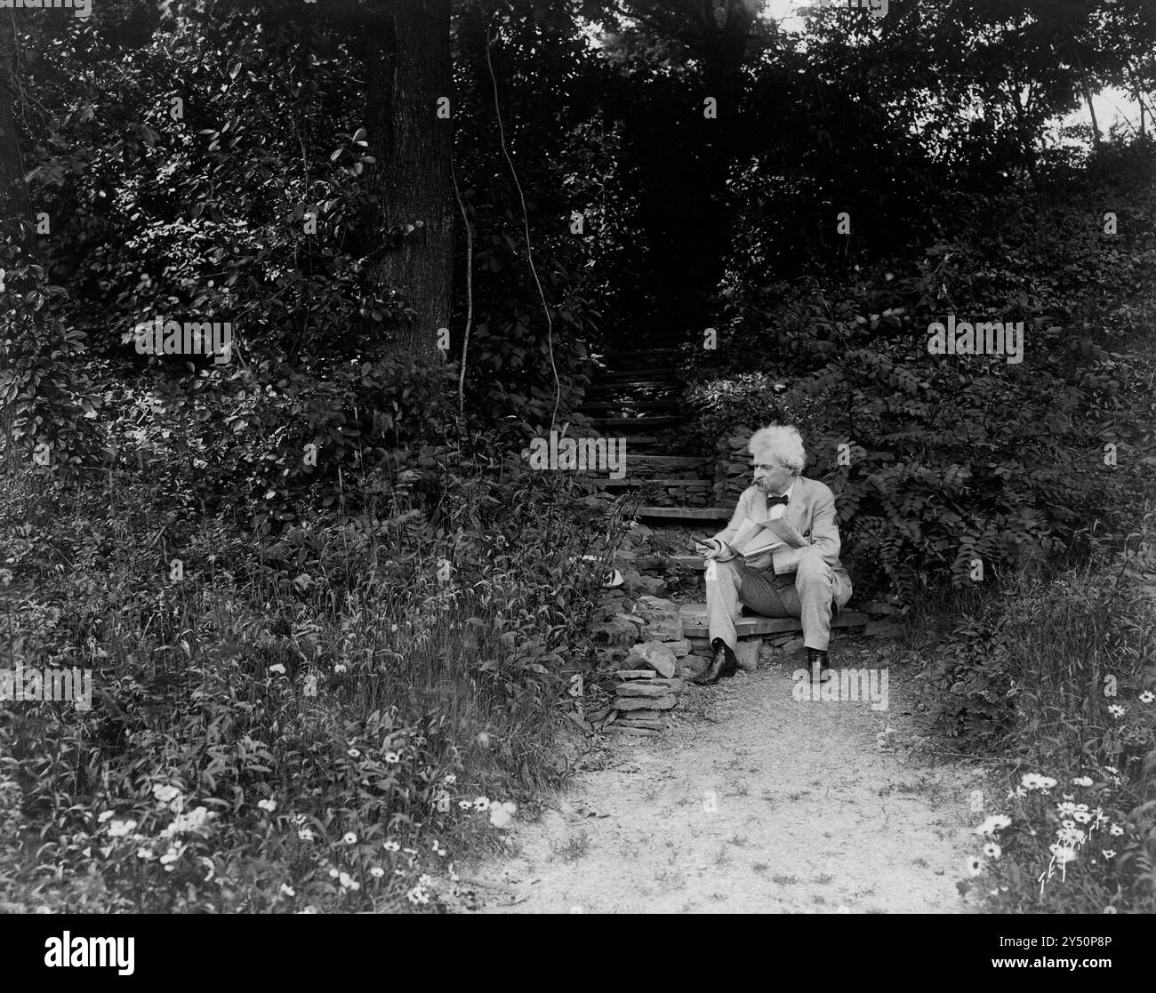 Mark Twain, full-length portrait, facing left, seated on step, outdoors ...