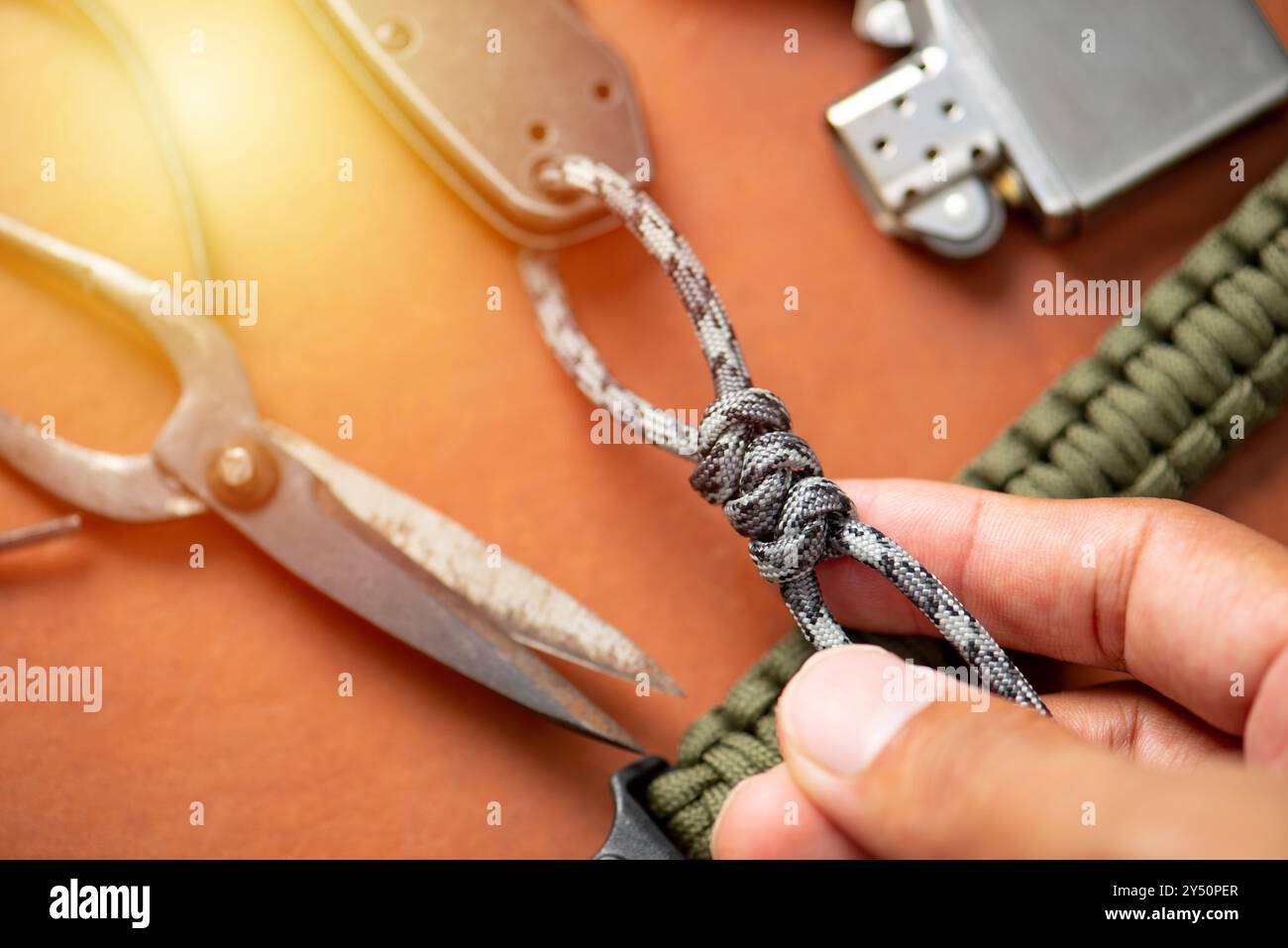 The man weaving lanyard from paracord rope. Paracord or Parachute cord ...