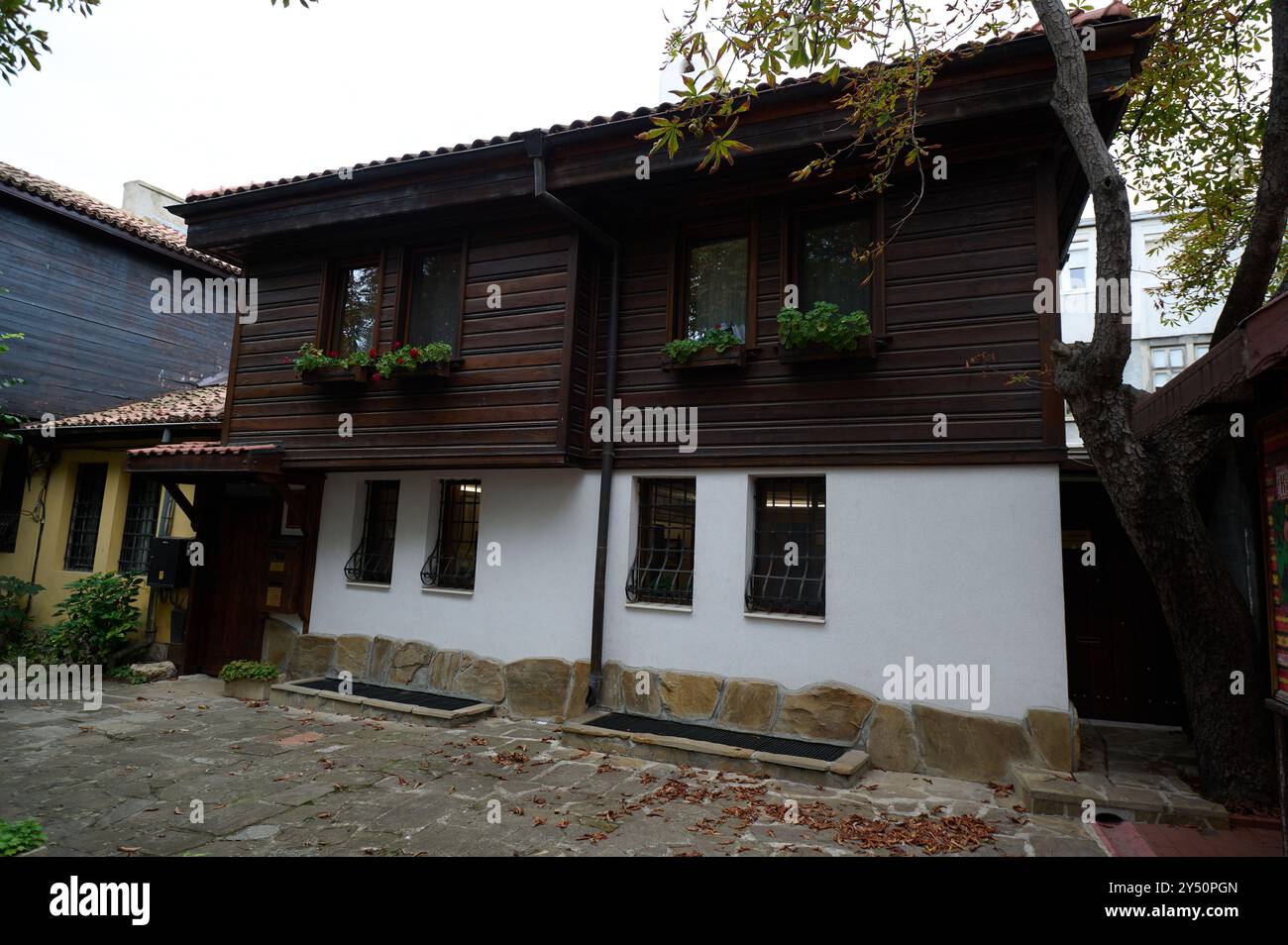 Traditional two-story wooden house with stone accents and green ...