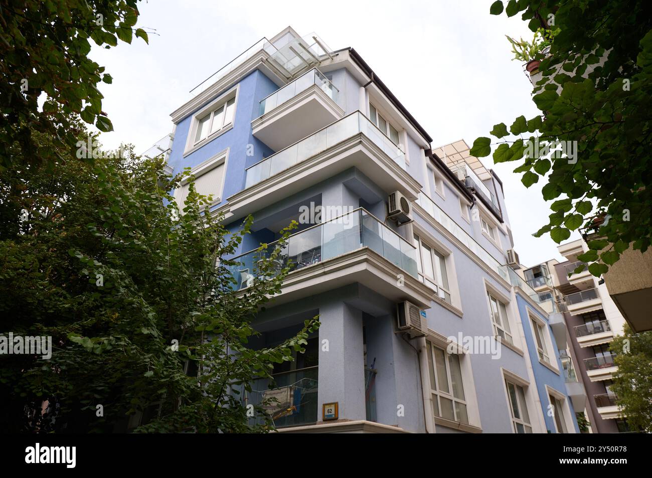 Modern blue residential building surrounded by lush greenery in an ...