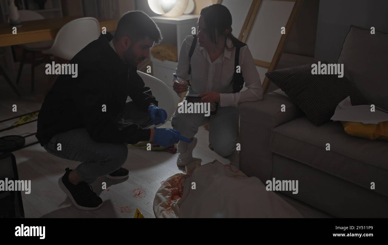 Man and woman investigators examine evidence at a dimly lit indoor ...