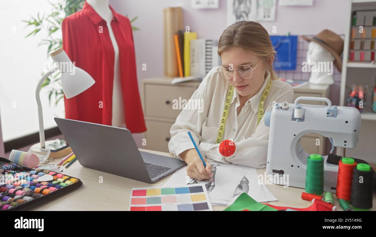 Focused young woman designing in a bright tailor shop with colorful ...