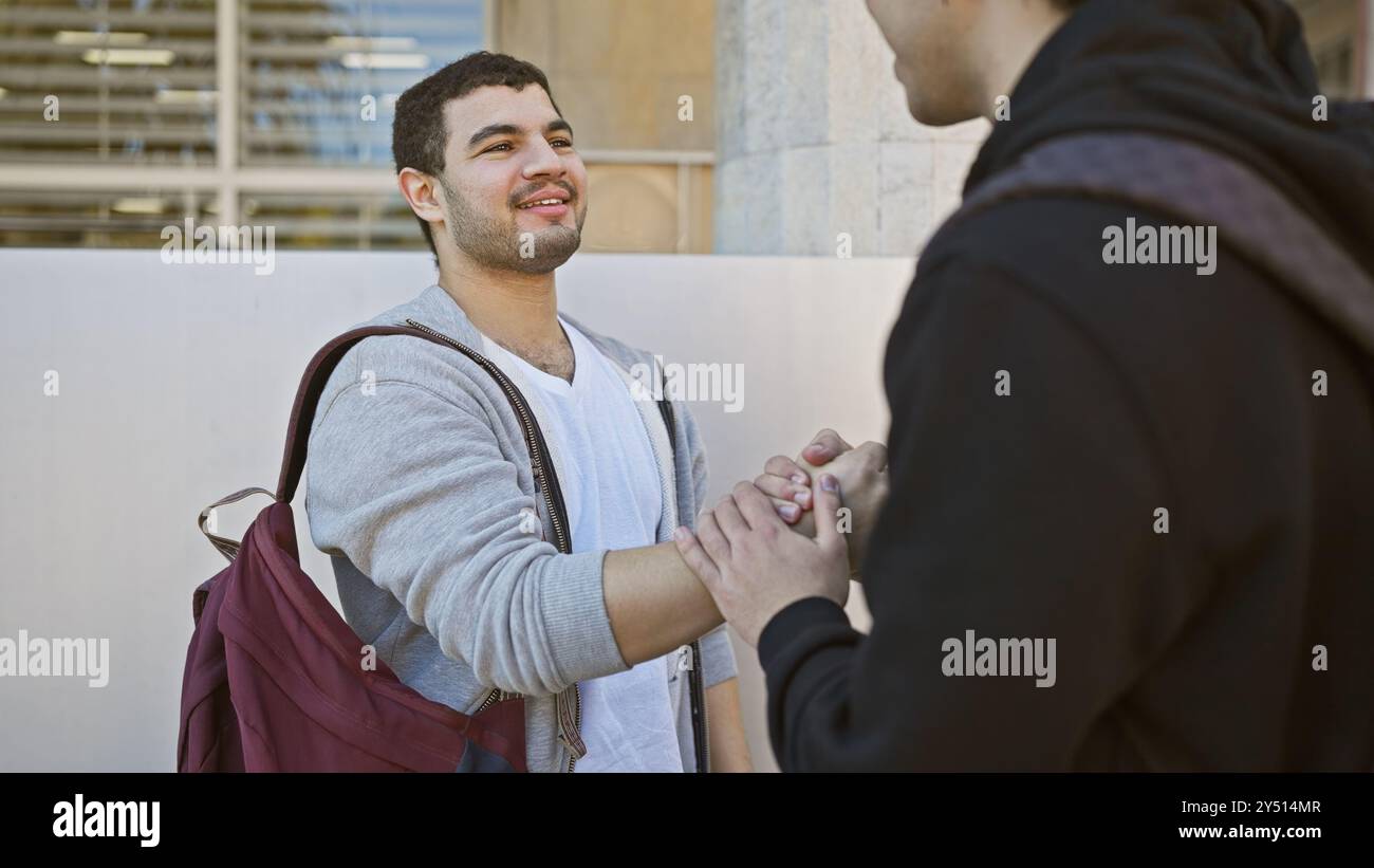 Two hispanic men shaking hands on an urban street, conveying friendship ...