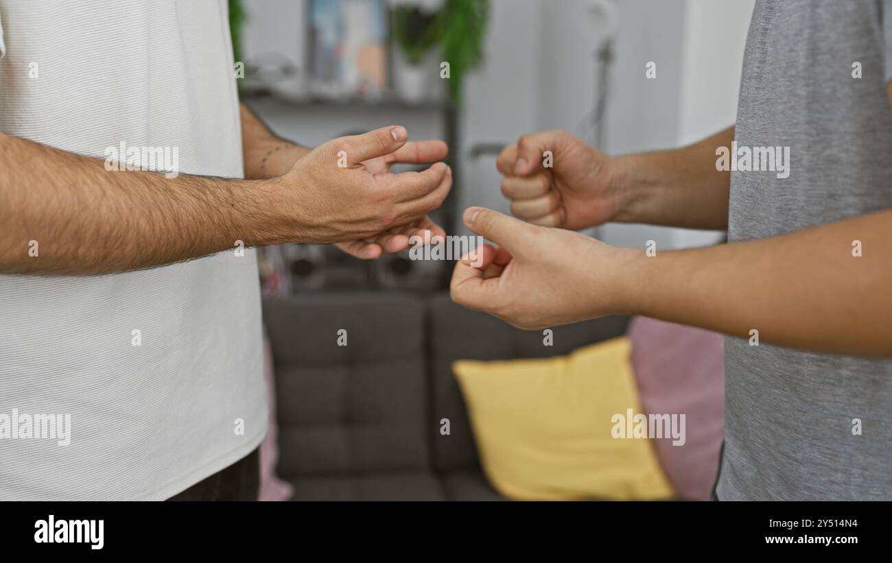 Two men engaging in a friendly rock-paper-scissors game indoors, with a ...