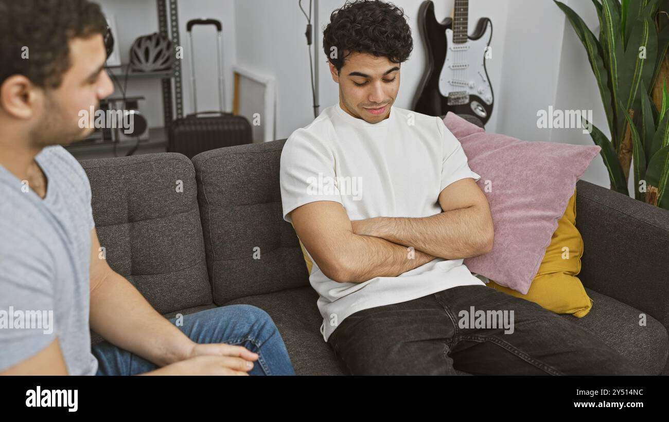 Two men sitting together on a gray couch in a modern living room ...