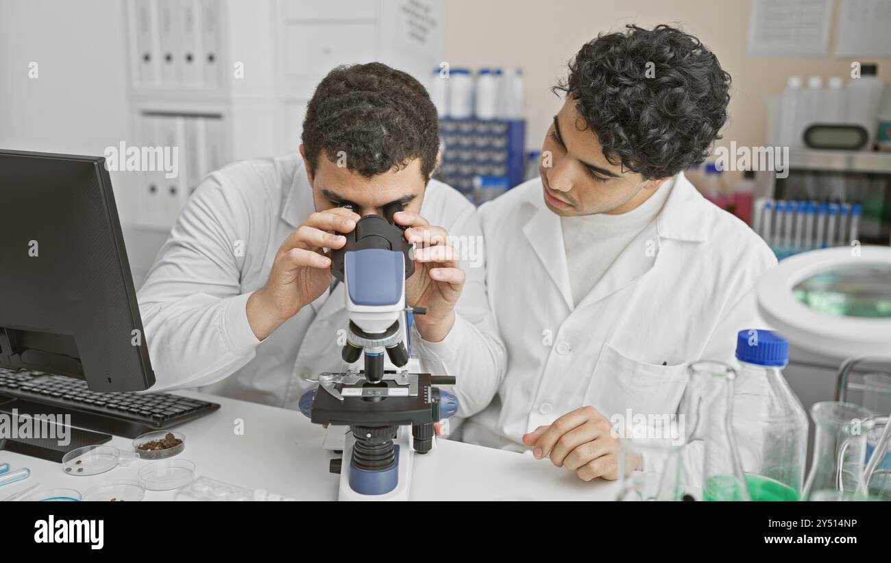 Two men in white coats collaborate using a microscope in a modern ...