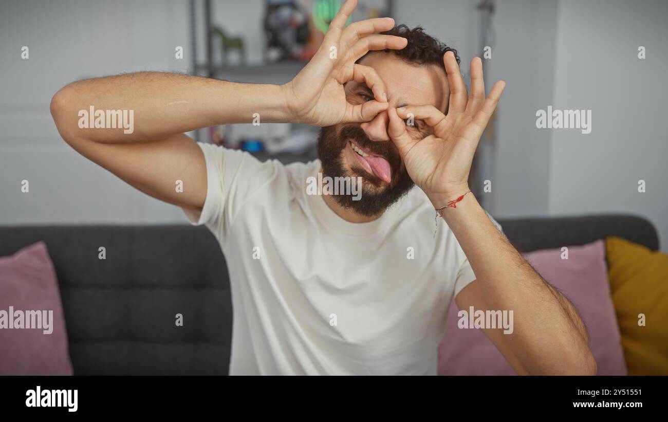 A playful bearded man making glasses gesture indoors in a casual home ... A playful bearded man making glasses gesture indoors in a casual home ...