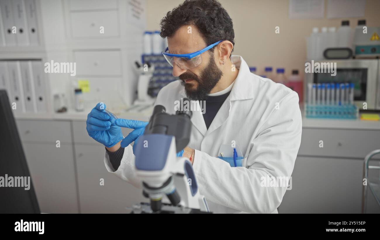 A bearded scientist examines a sample through a microscope in a ...
