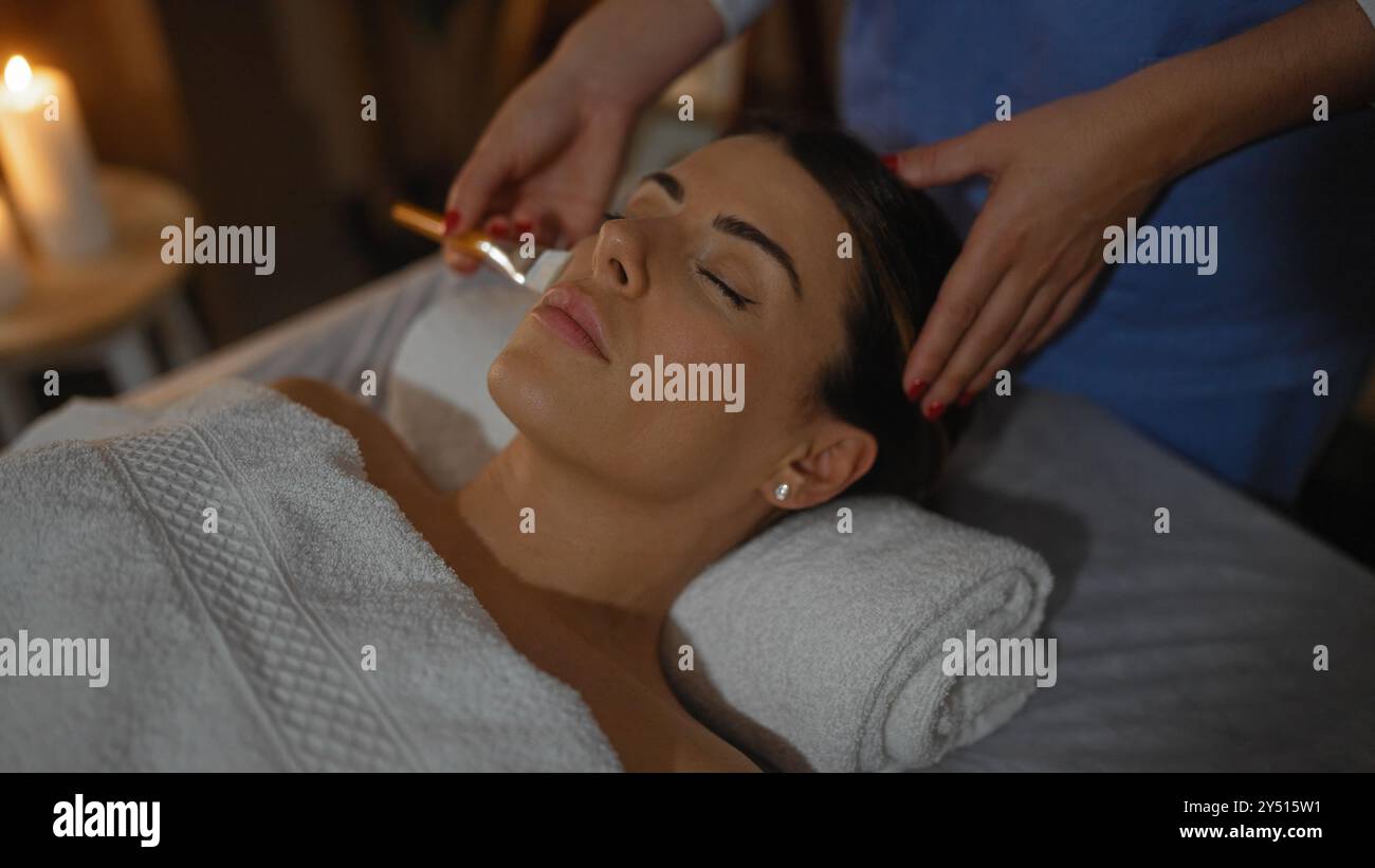A woman receiving a relaxing facial treatment in a spa room with soft ...