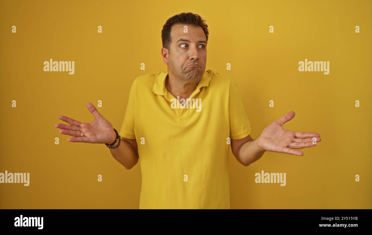 Hispanic man showing confused gesture isolated over yellow background ...