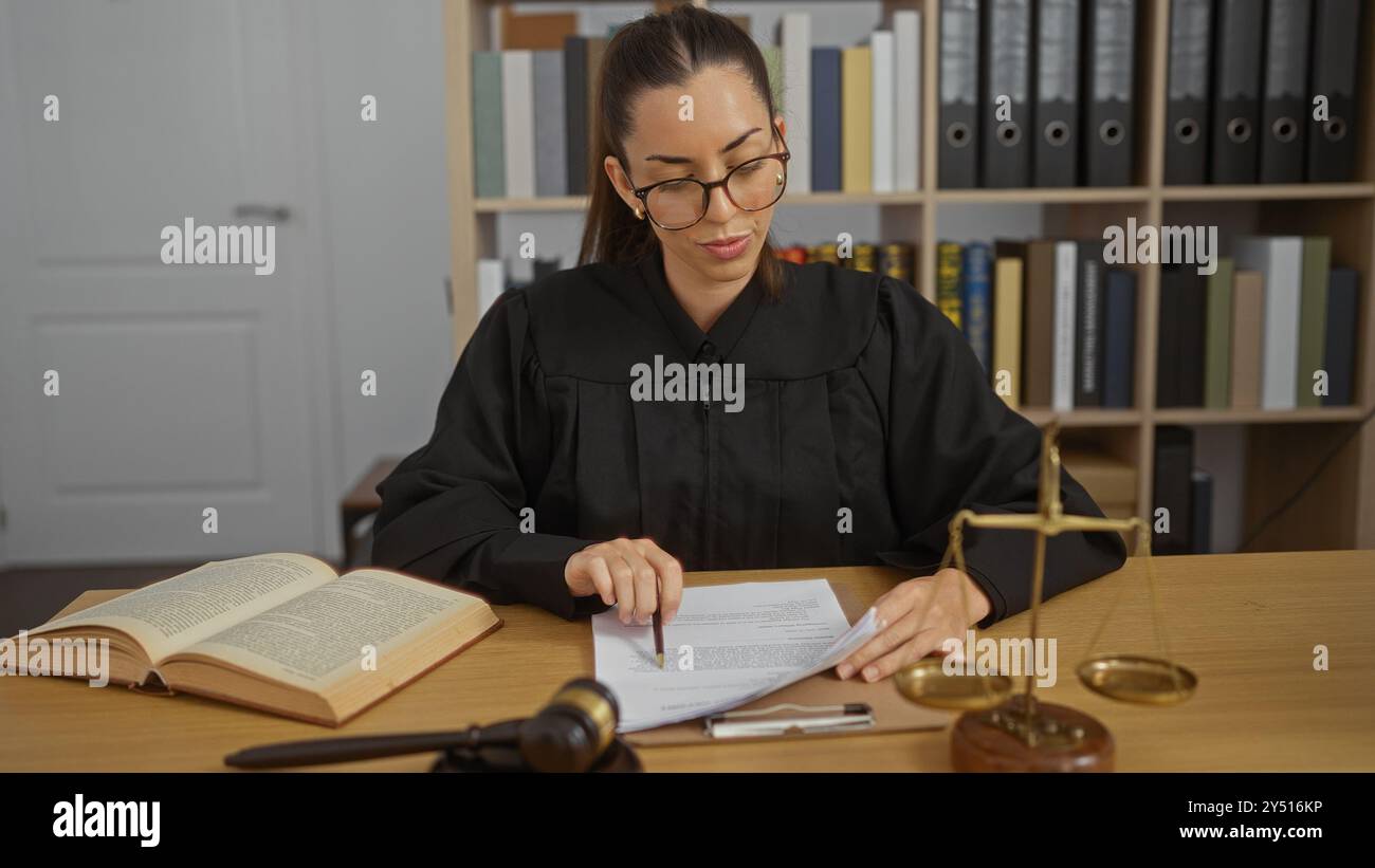 Attractive hispanic brunette woman judge reading documents in a ...