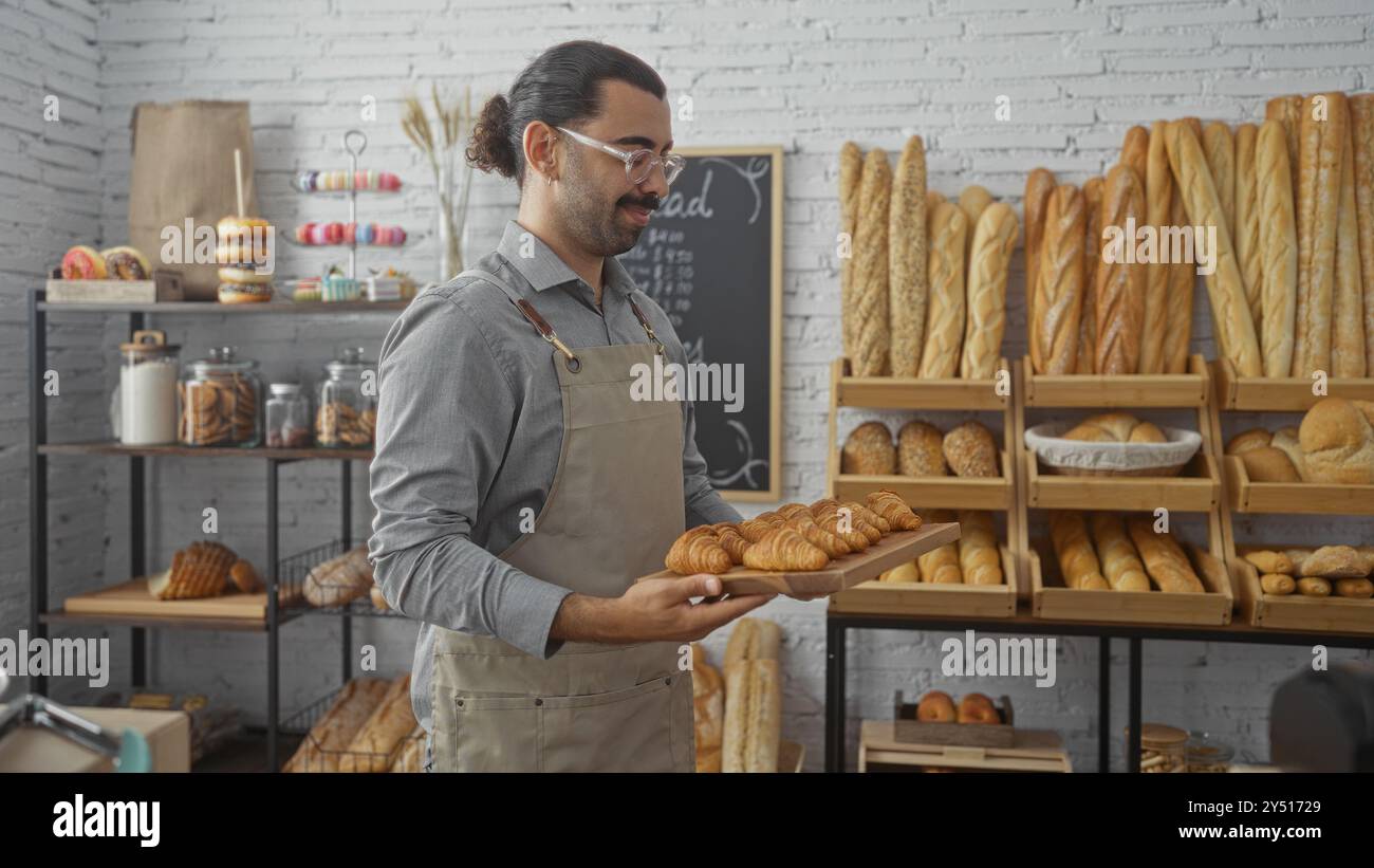 Handsome young man with moustache holding tray of croissants in bakery ...