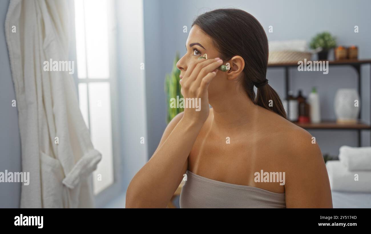 Woman applying facial massage with roller in spa room showcasing self ...