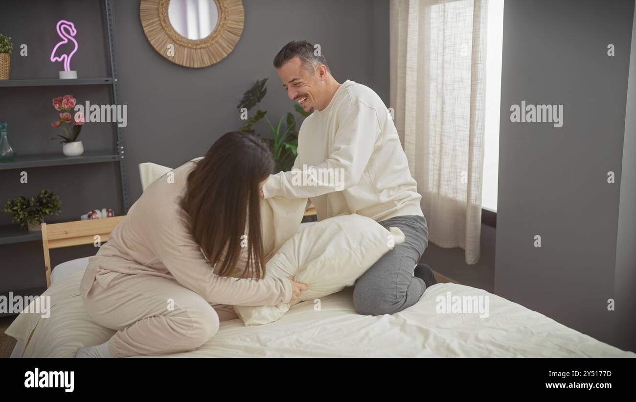 A happy couple enjoys a playful moment together on the bed in a cozy ...