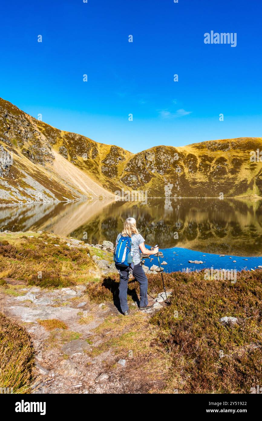 A walker at the stunning body of water called Loch Brandy, a mountain ...