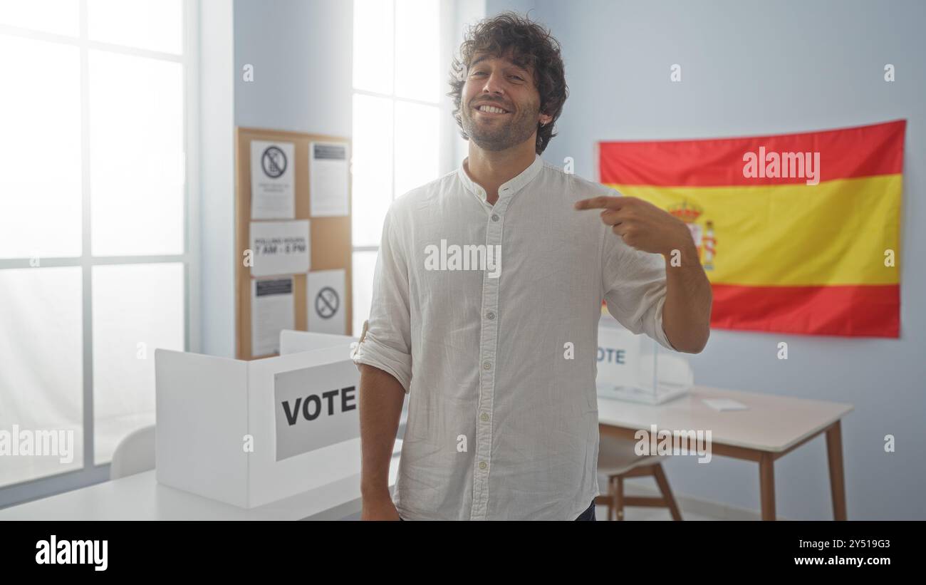 Young man standing in an electoral room with spanish flag pointing at ...