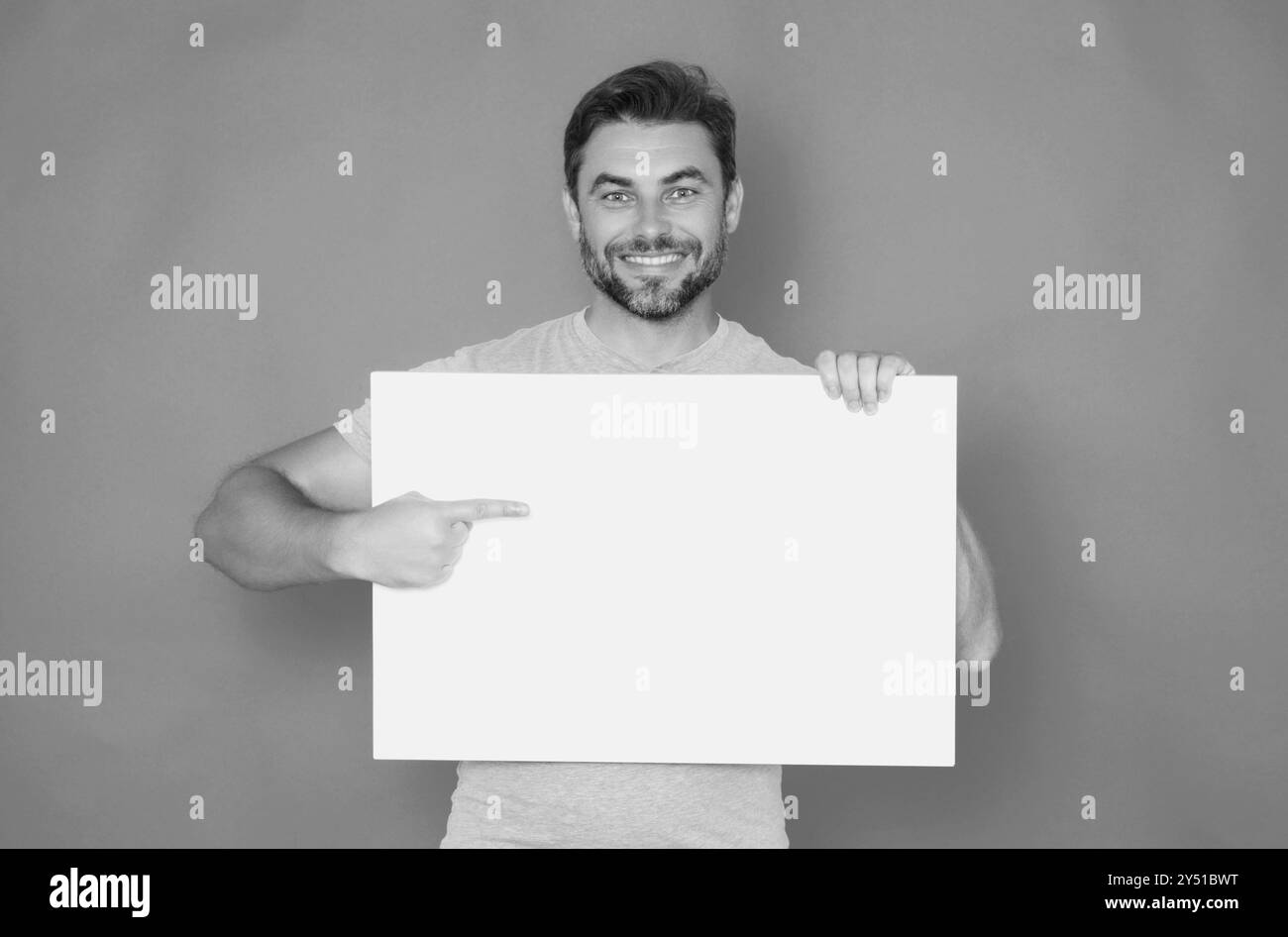 Happy man holding empty board and pointing finger on board. Guy showing ...