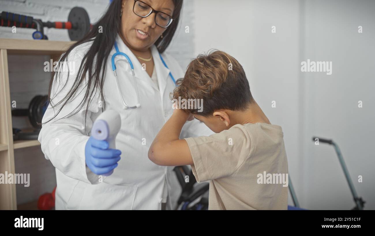 A woman doctor examines a boy patient in an indoor physiotherapy clinic ...