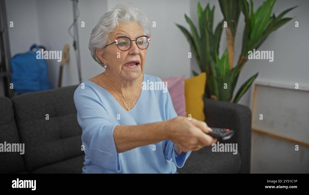 Elderly woman watching television comfortably in her modern living room ...