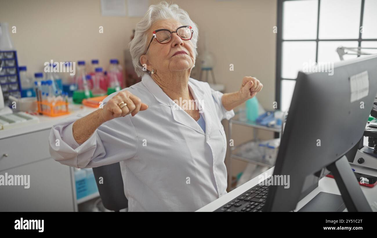 A senior woman scientist stretching in a laboratory, showing a moment ...