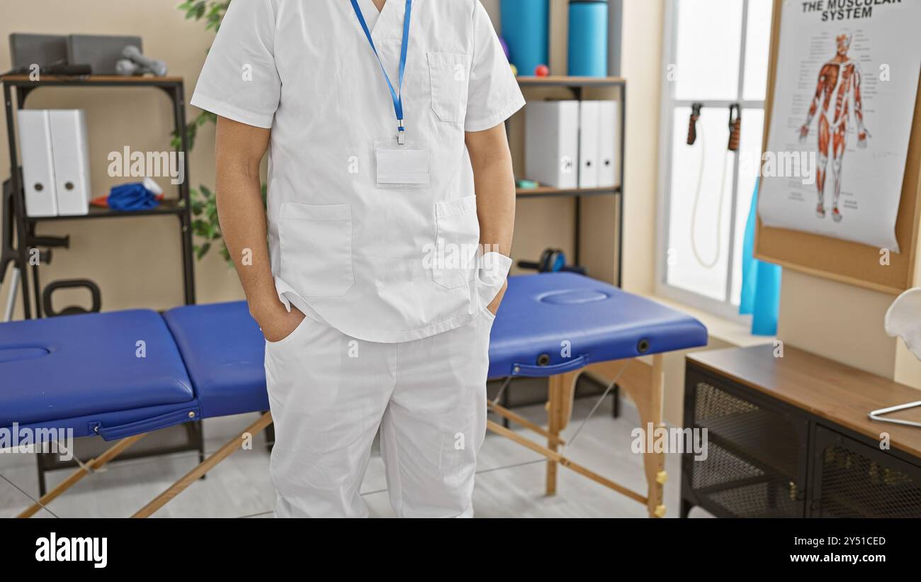 Hispanic man in white scrubs standing in a physical therapy clinic room ...